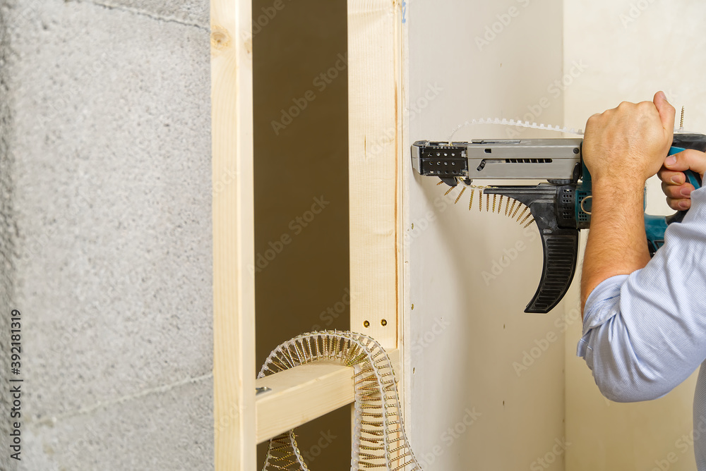 Room repair. Building. Worker fastens drywall with a screwdriver close ...
