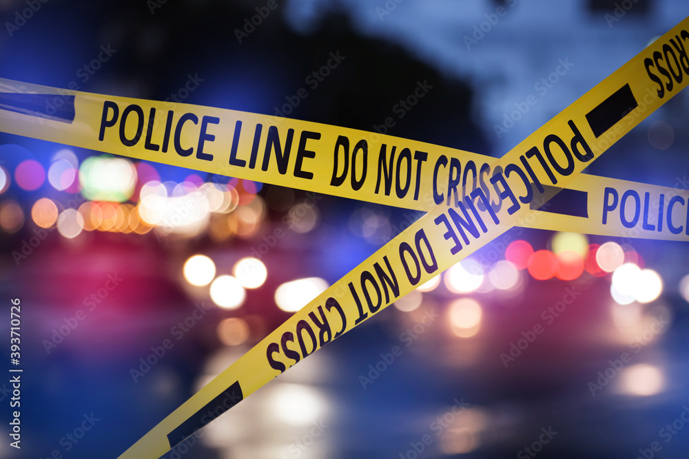 Yellow law enforcement tape isolating crime scene. Blurred view of city ...
