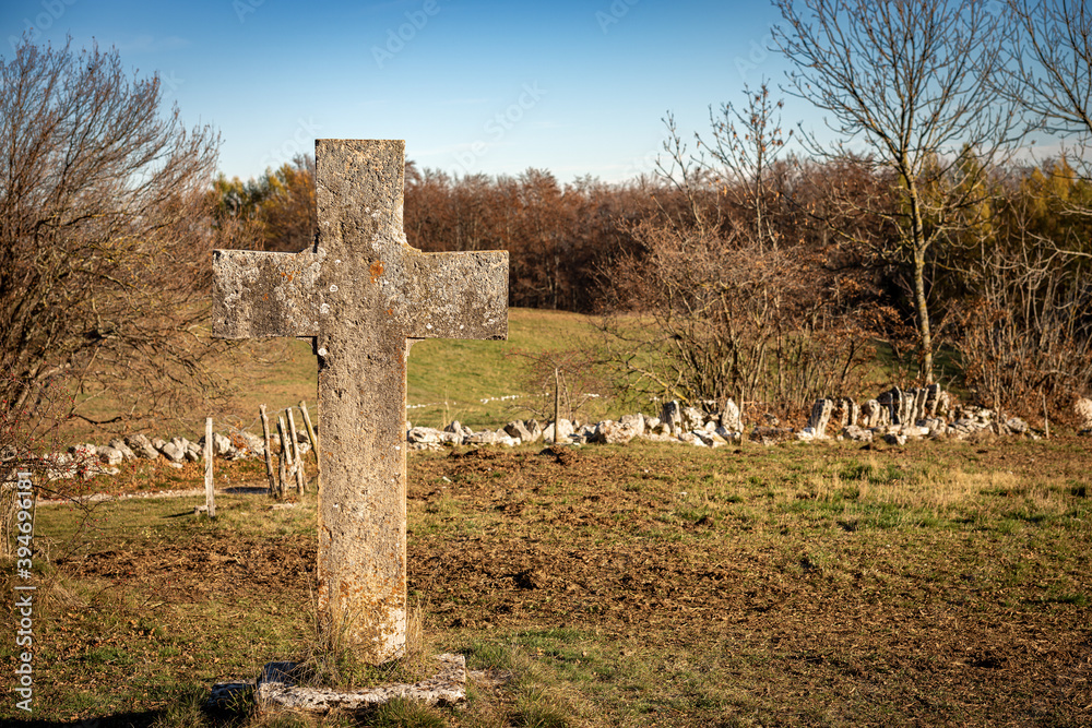 Ancient stone Christian cross in a rural scene near the small village ...