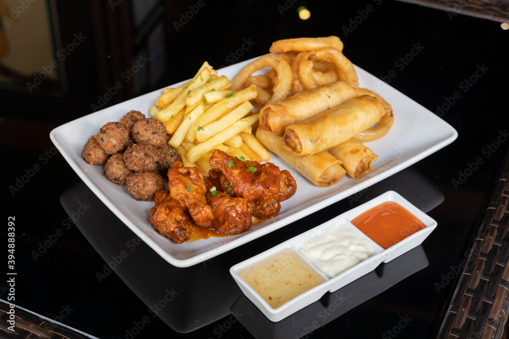Sharing platter with spring rolls, honey BBQ chicken drumsticks, onion ...