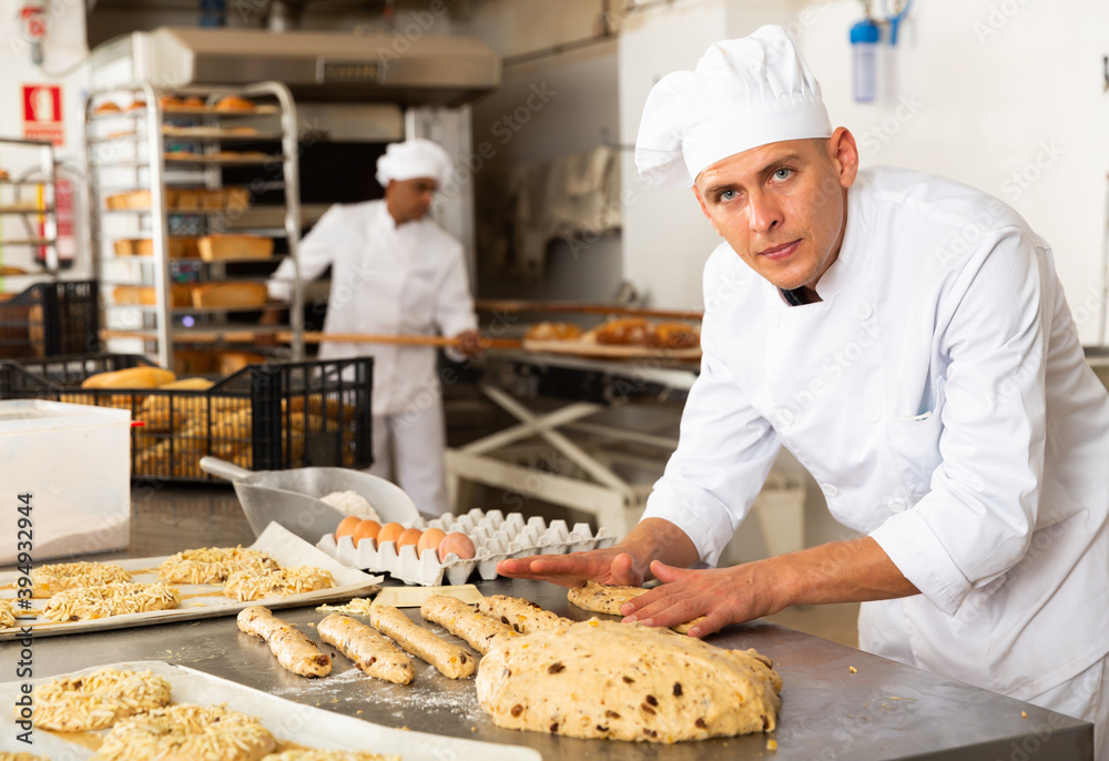 Working at bakery, male baker kneading dough and shaping baguettes on ...