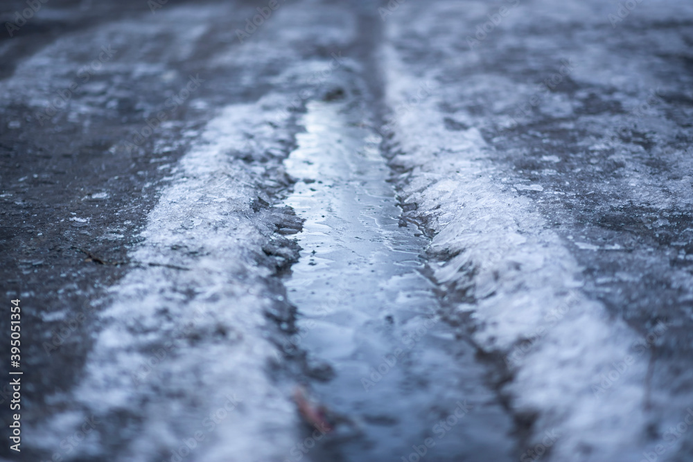Frozen water in a puddle. Sunlight reflects off the frozen surface of ...