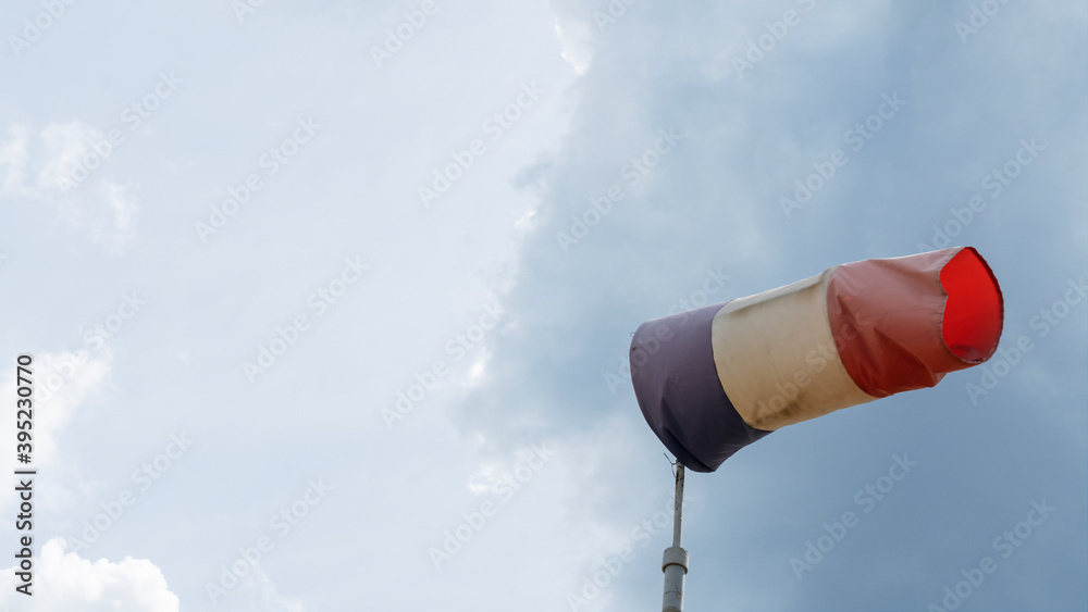 Flying windsock wind vane with red, white and blue lines on dramatic ...