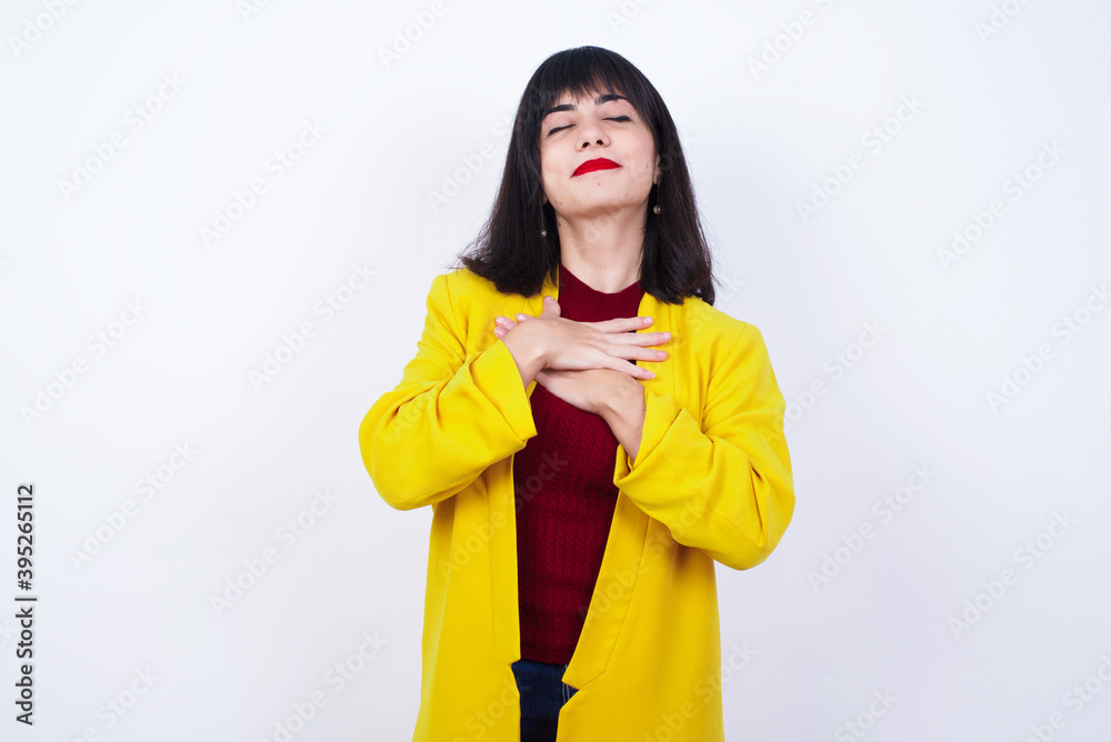 Young beautiful caucasian woman closes eyes and keeps hands on chest ...