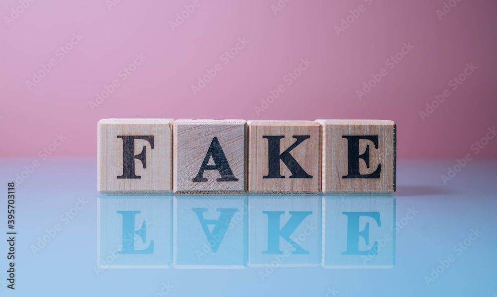 Text FAKE on wood cube blocks. The letters FAKE written on the cubes in ...