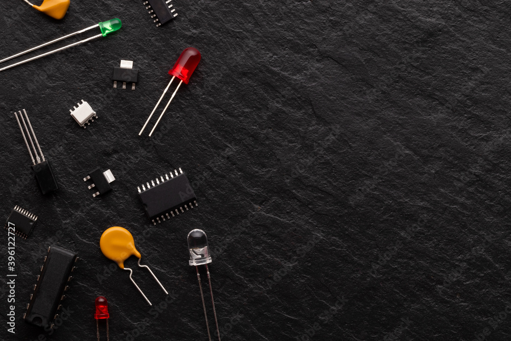 Electronic components over black stone background with copy space. There are microcontrollers ...