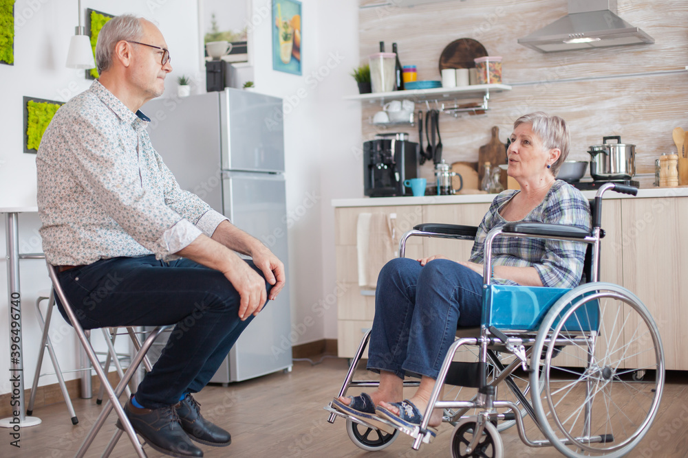 Foto de Stock Retired invalid woman in wheelchair having a conversation ...