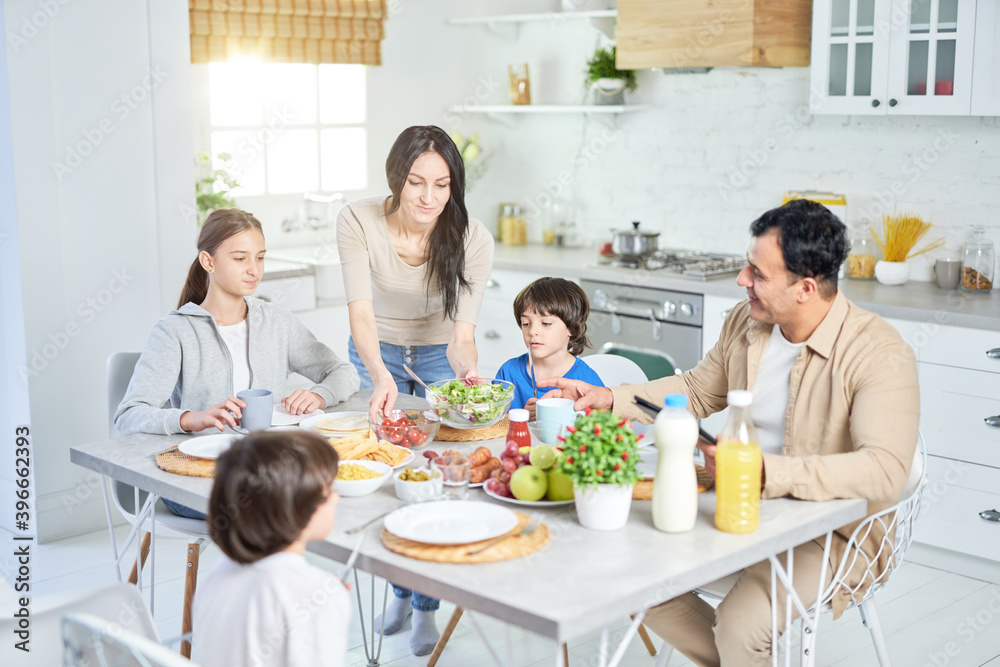Share food. Caring hispanic woman serving salad for her husband and ...