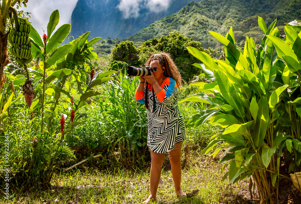 Pretty woman with curly hair taking photographs with moderne camera on ...