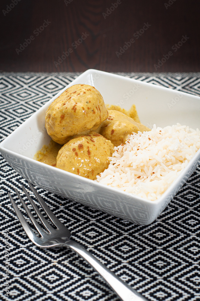 Danish meatballs in curry sauce served in a square white bowl with ...