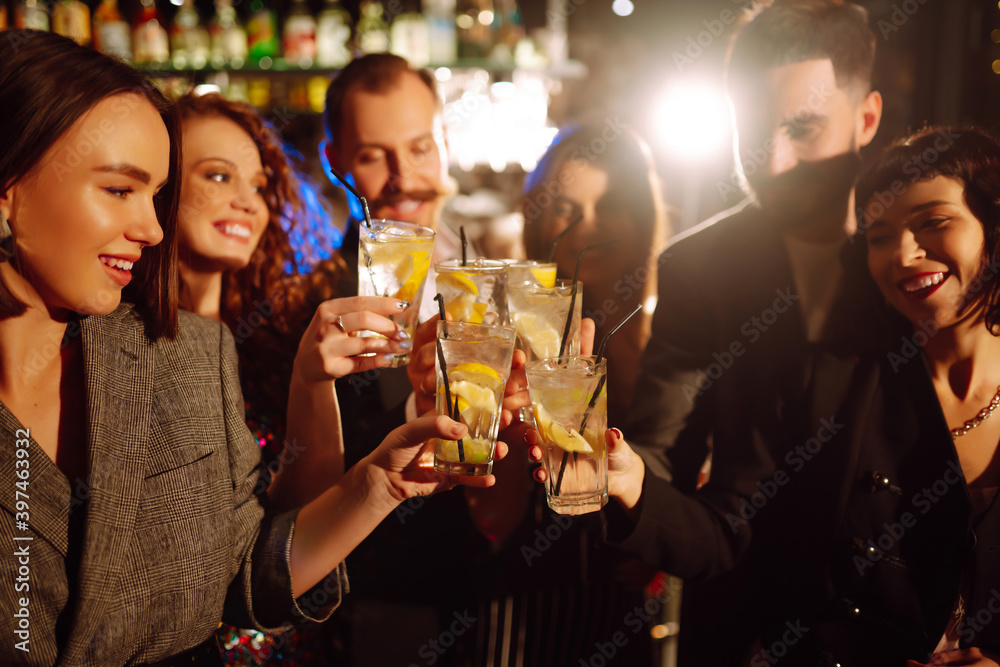 Group of friends cheering and drinking cocktails together at the bar ...