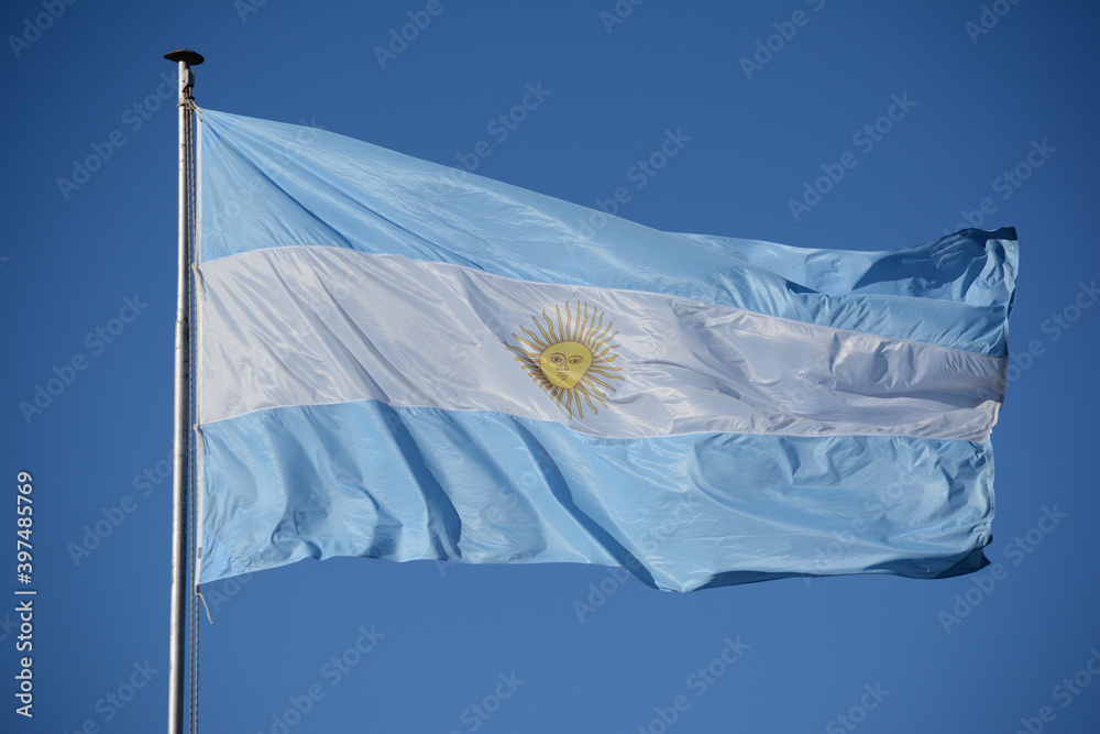 Bandera de la República Argentina de tela flameando en el cielo celeste ...