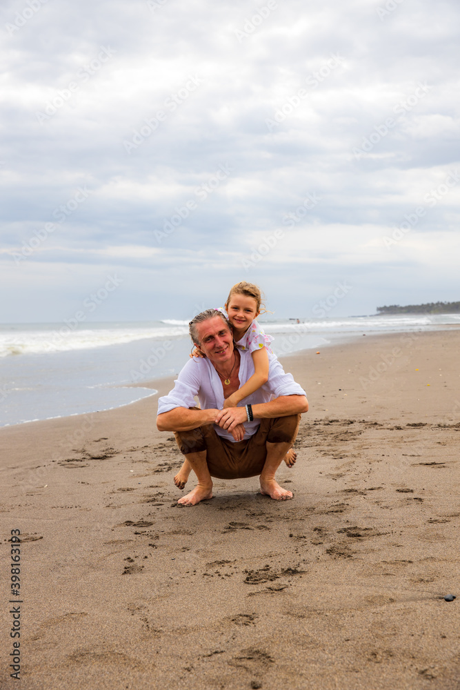 Daughter hugging father. Man hunkering down on the sand. Relation ...