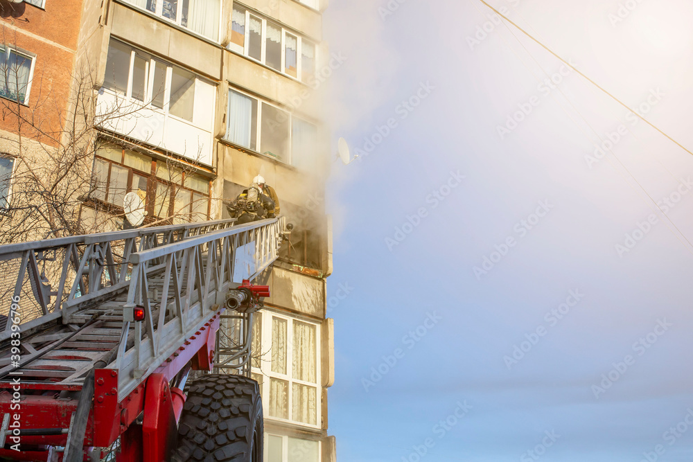 a firefighter extinguishes a balcony, in a high-rise building, from a ...