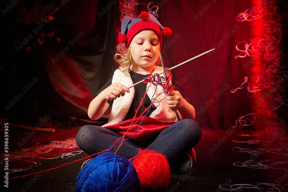 A pretty little girl who looks like a dwarf or elf is knitting with ...