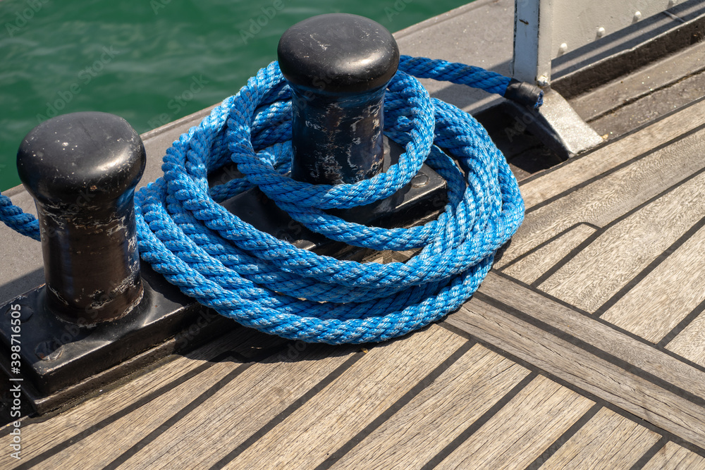 Foto de Stock Blue rope of mooring line lying rolled around mooring ...