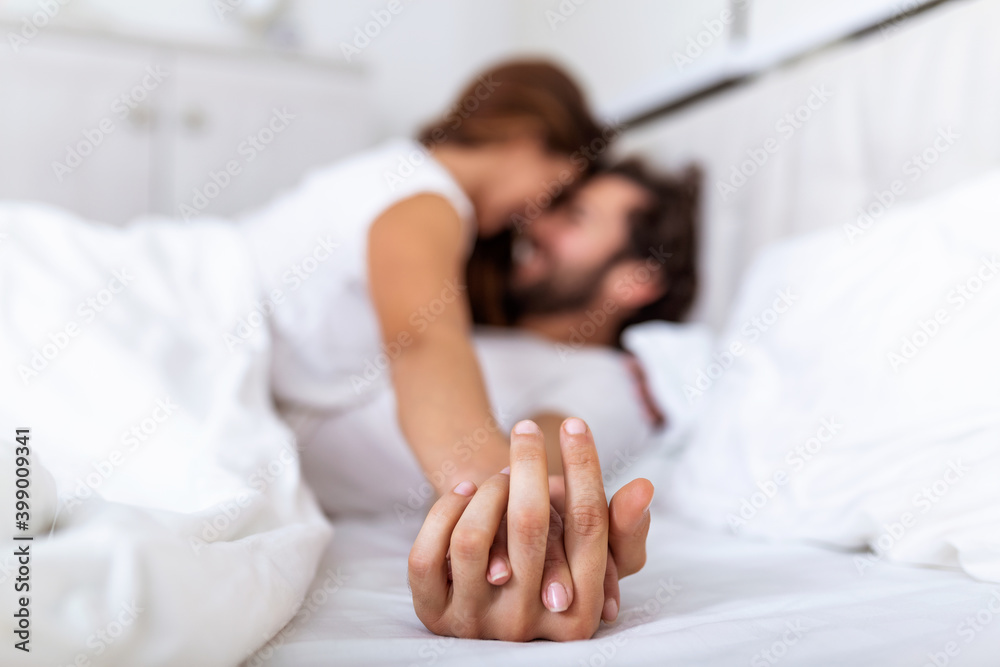 Romantic couple in bed enjoying sensual foreplay. Focus on hands man ...