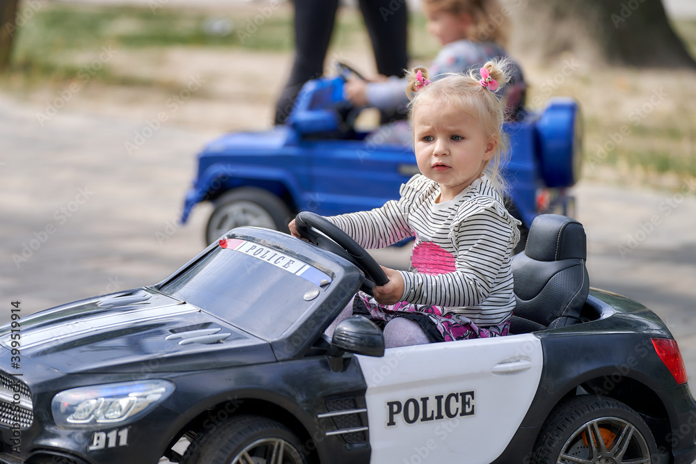 Foto de Stock Funny little girl in a children's car driving. Young ...