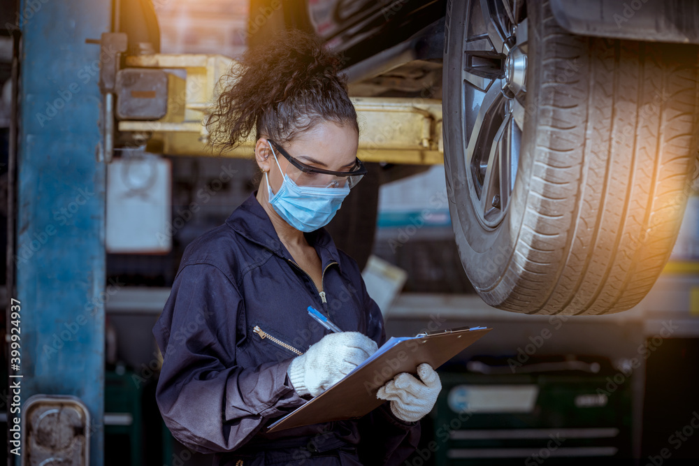 Car mechanic under checking car wheels at garage for maintenance or ...