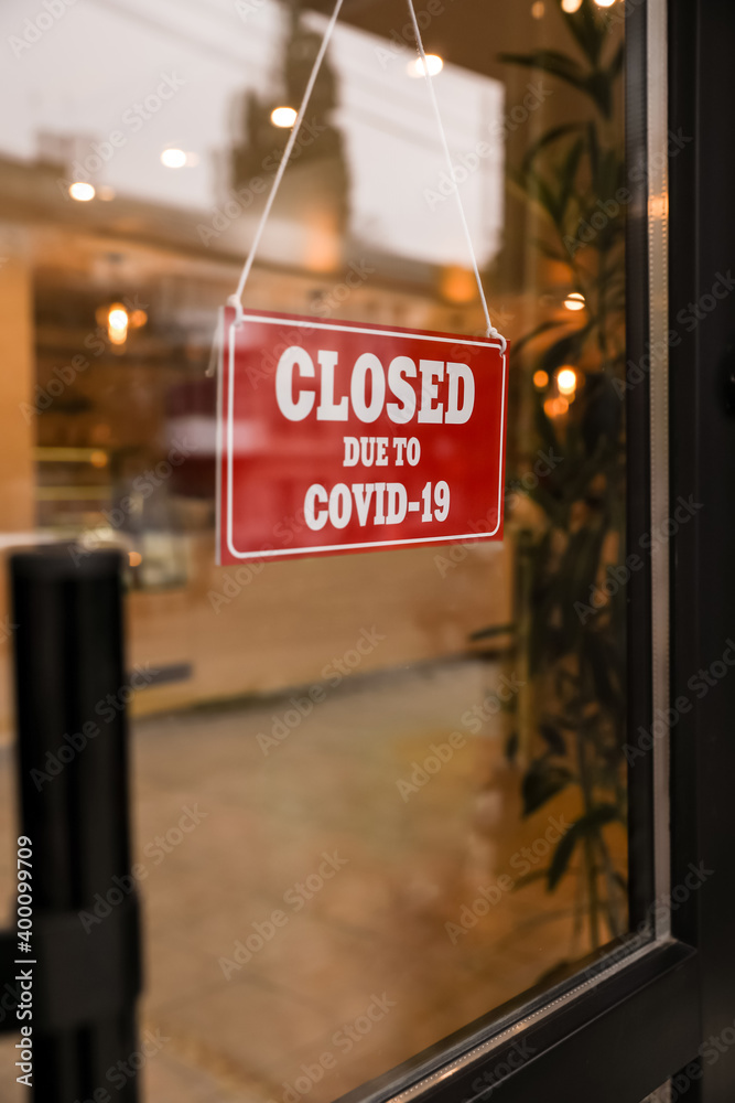 Red sign with words "Closed Due To Covid-19" hanging on glass door ...