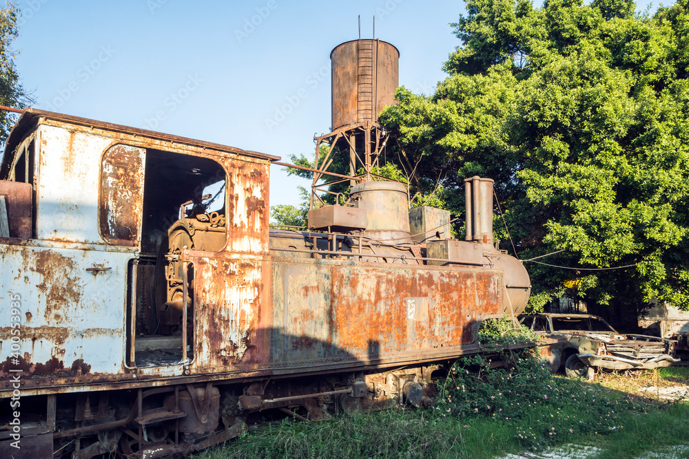 Old rusty abandoned train with a broken car and a rusty elevated water ...