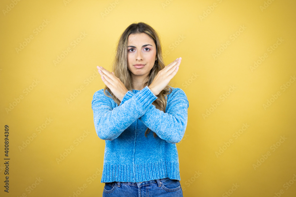 Pretty blonde woman with long hair standing over yellow background ...