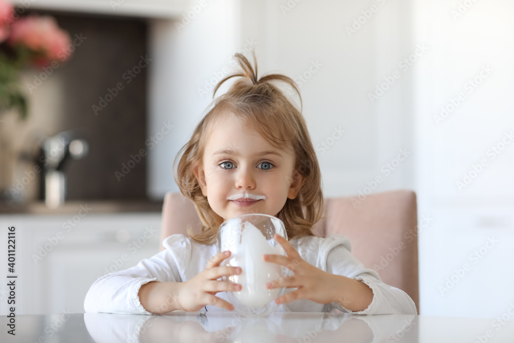 Blond cute baby girl with blue eyes with traces of milk on the lips is ...