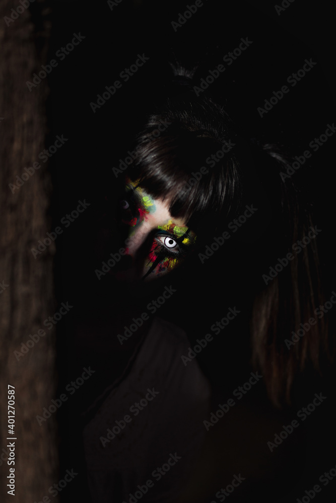 Creepy female with creative makeup and in contact lenses standing near ...