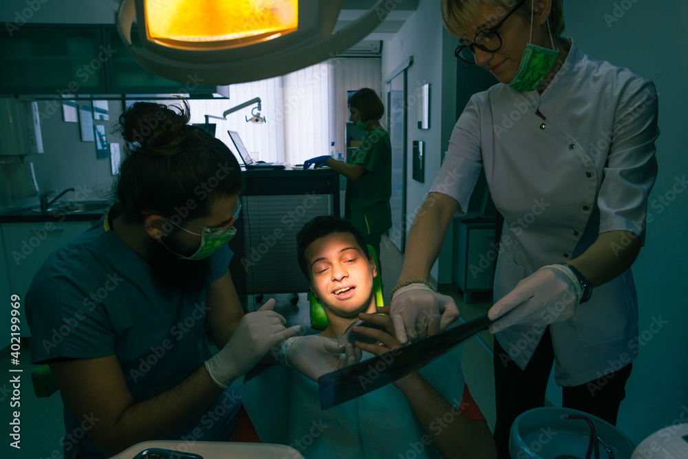 Male dentist and female assistant showing a young boy patient his teeth ...