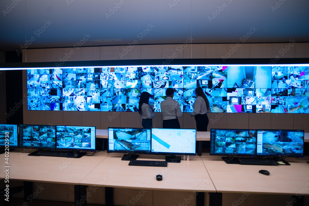 Security guards standing in front of a large CCTV monitor at the main ...