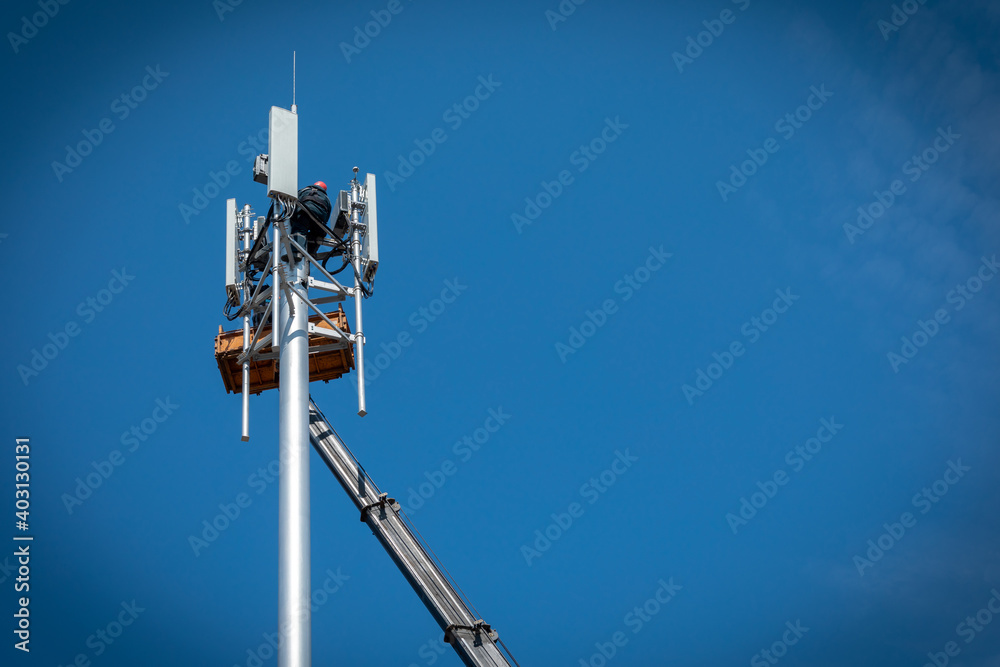 Workers install cellular base station with transmitters 3G, 4G, 5G and antennas on cell tower on ...