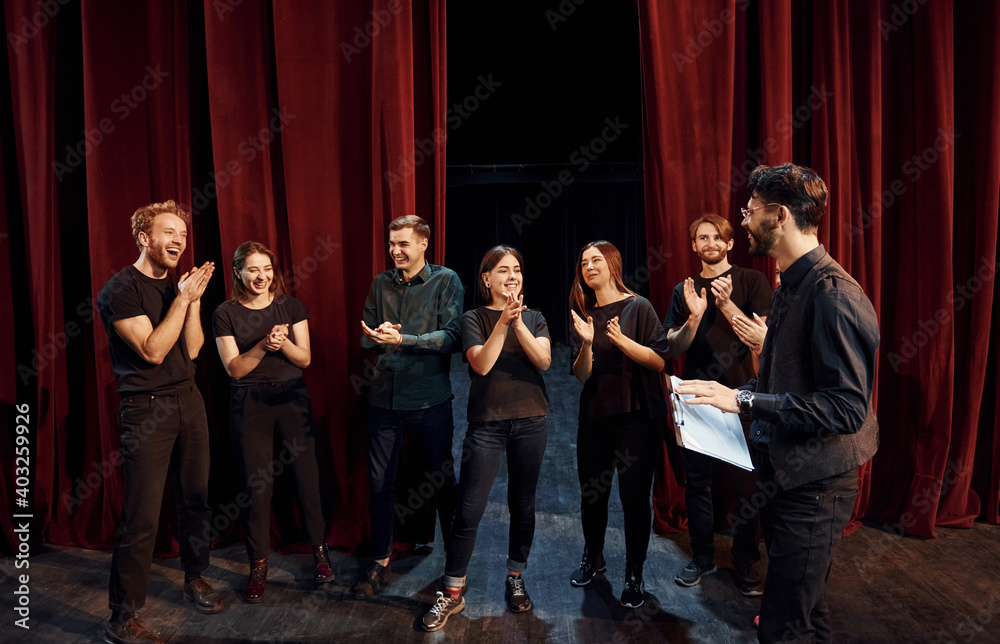 Man is practicing his role. Group of actors in dark colored clothes on ...