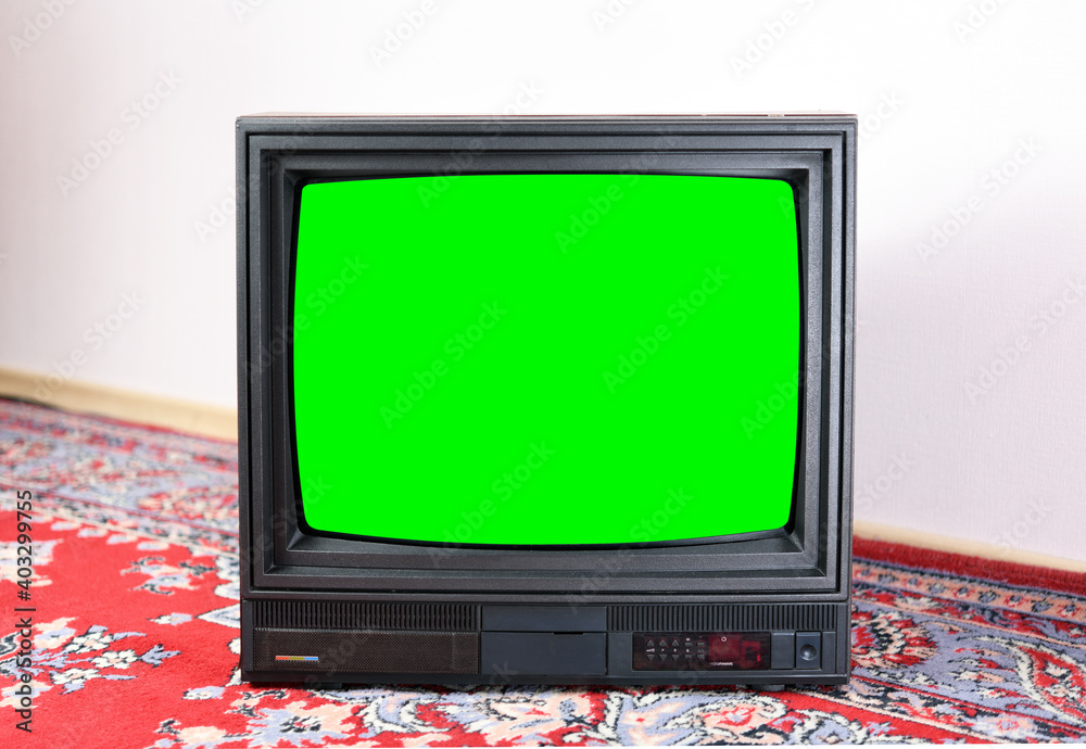 An old vintage TV with a green screen sits on a bright Soviet carpet on ...