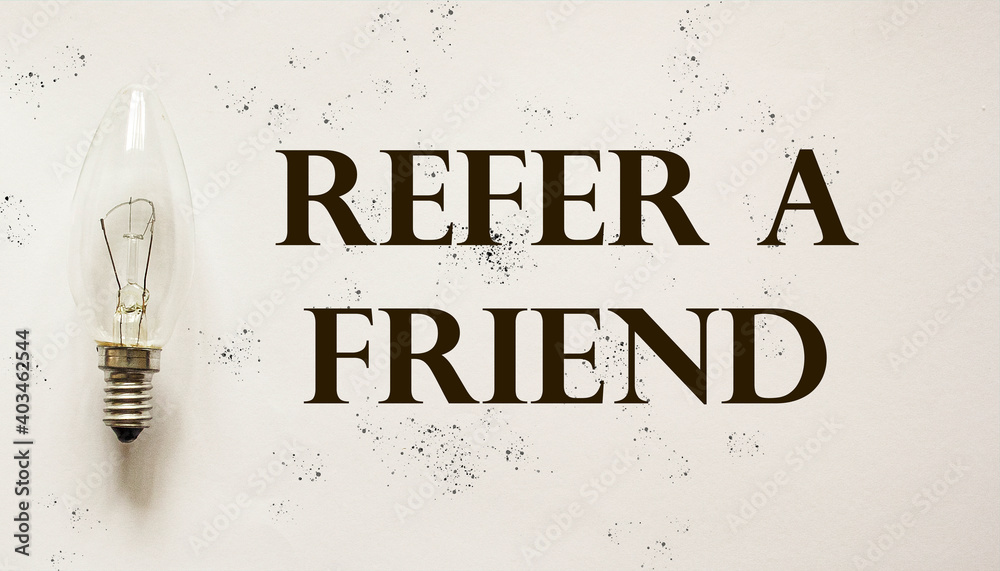 Refer a friend text written on vintage surface, next to light bulb ...