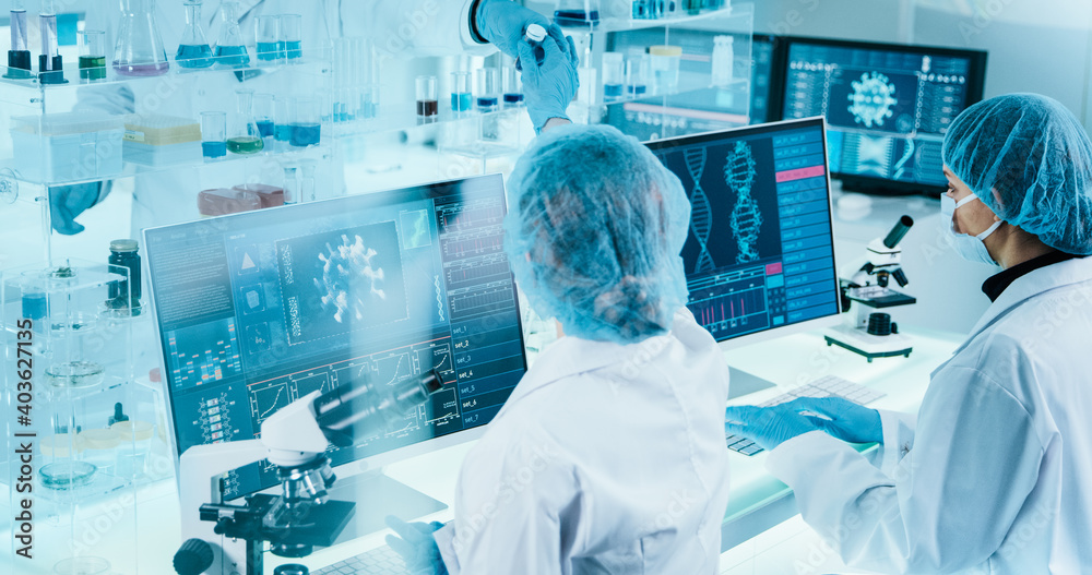 Two female scientists sitting in front of computer screens with ...