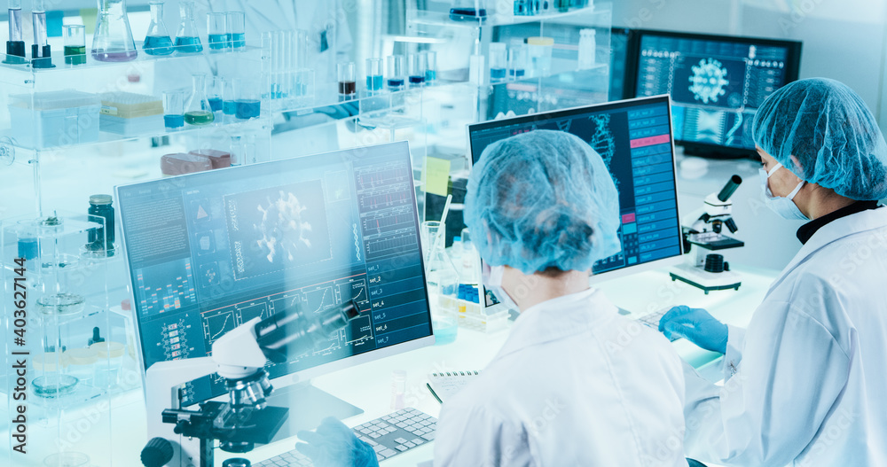 Two female scientists sitting in front of computer screens with ...