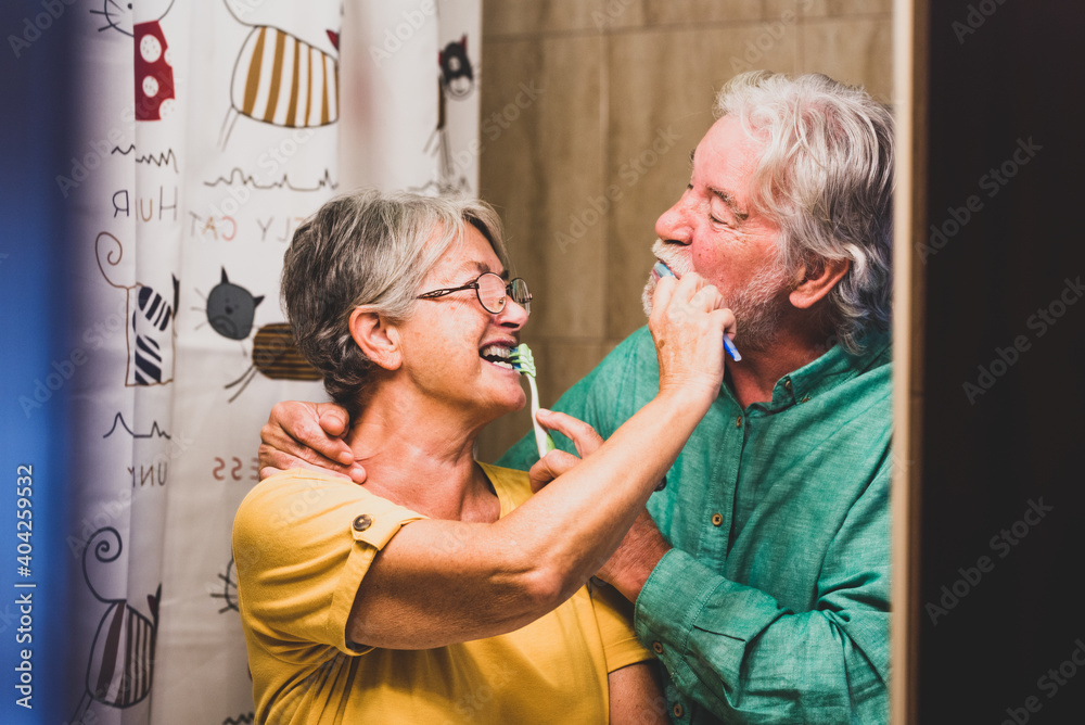 couple of two happy and smiling seniors brushing their teeth of they ...