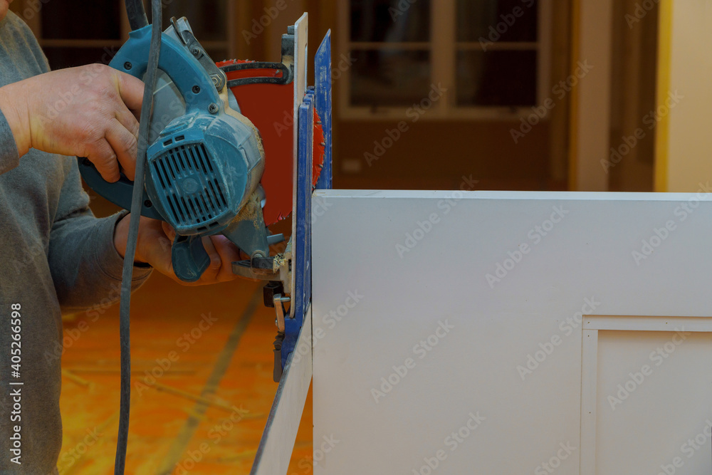Wood siding contractor using an electric compound miter saw to cut door ...