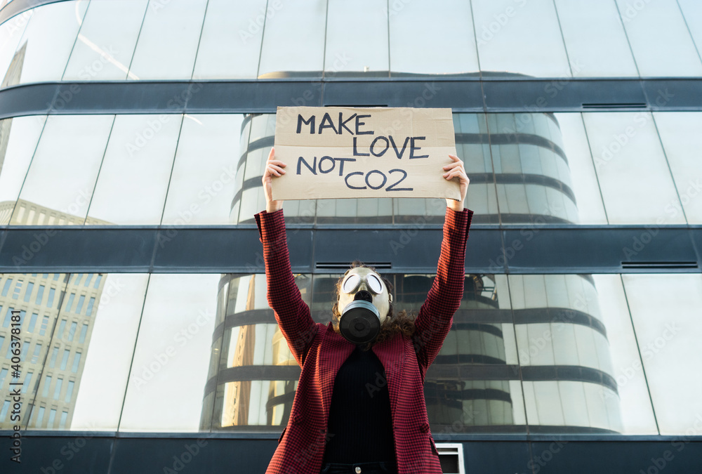 Woman with gas mask in a city between skyscrapers with a banner with ...