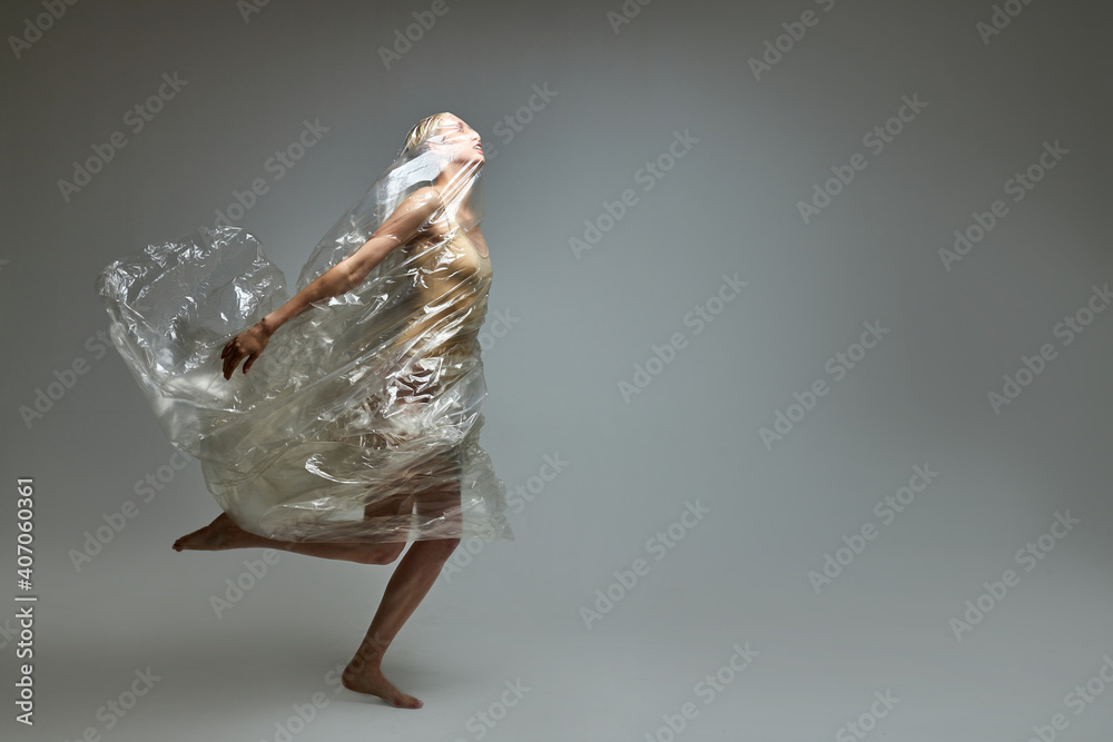 side view on female in a plastic bag, breaking free from plastic trash ...