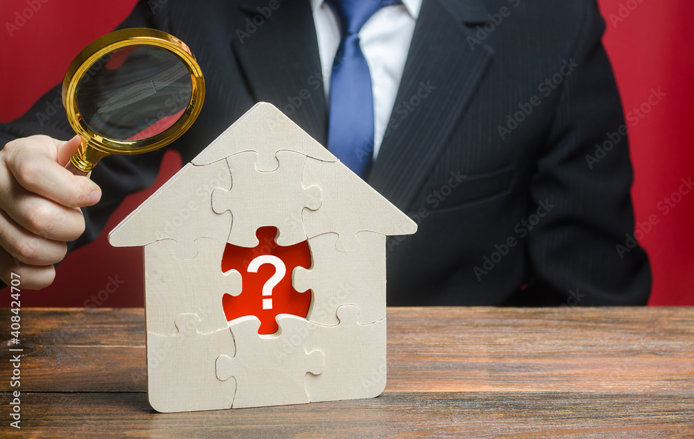 A man examines a house with a missing puzzle inside. Property valuation ...
