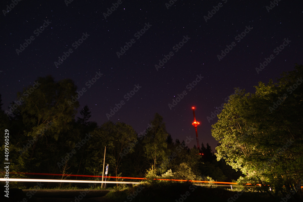 Radio tower at night and silhouette of trees in the forest with road ...