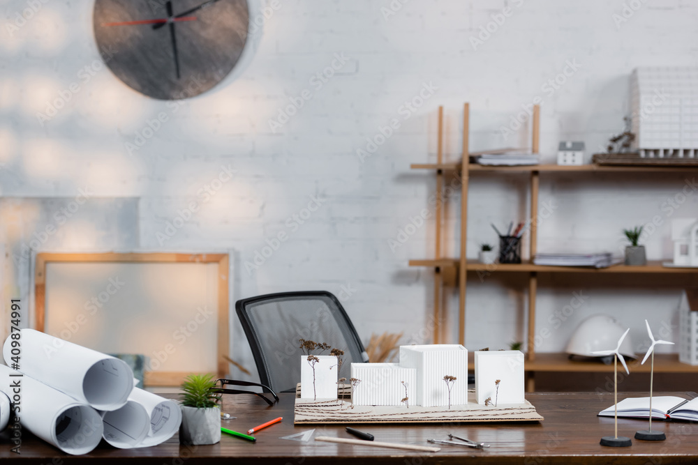 rolled blueprints, architectural maquette, and wind turbines models on ...
