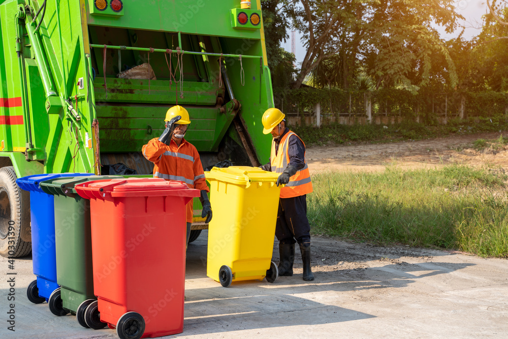Two refuse collection workers loading garbage for trash removal. Stock ...