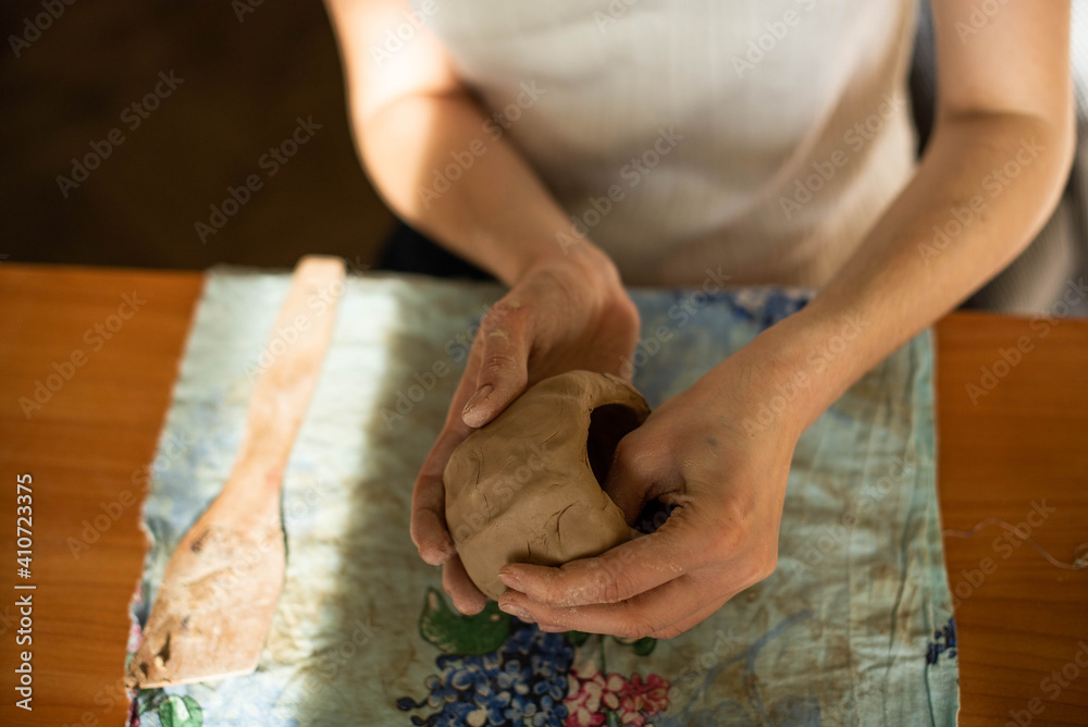 Pottery. A girl with a string in her hands cuts the top layer off clod ...
