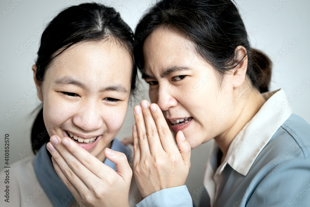 Asian mother whispering gossiping in her daughter ear,adult woman look ...