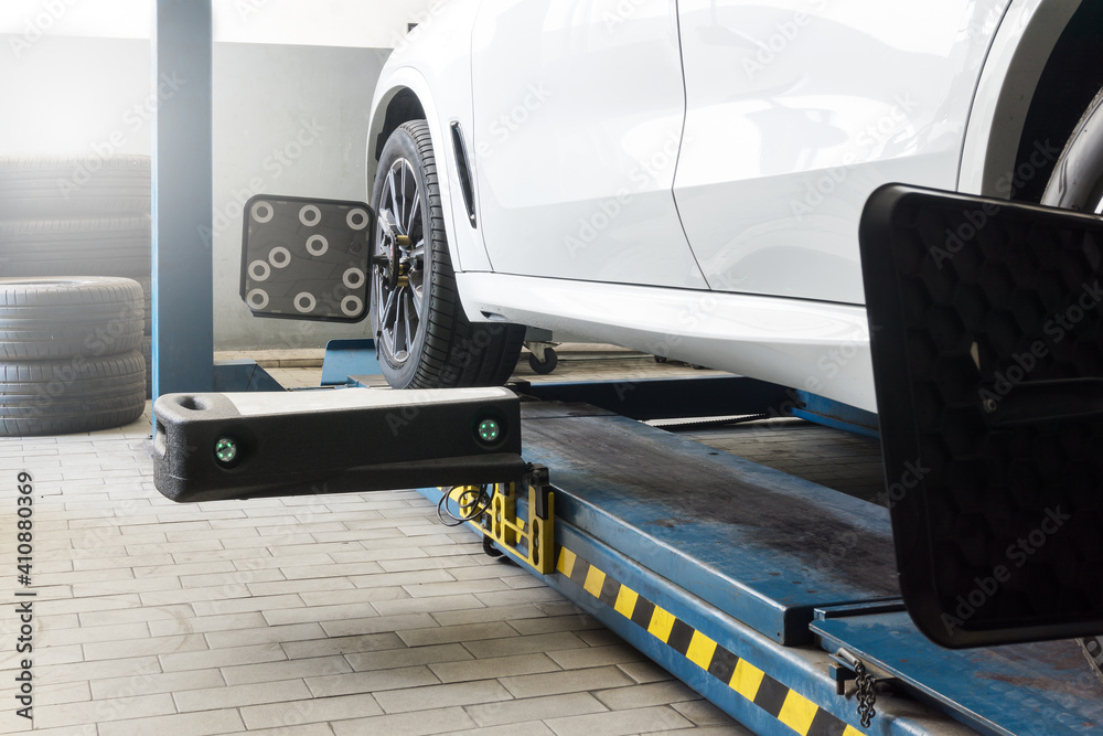 Car on wheel alignment station with sensor and laser reflector on wheel ...