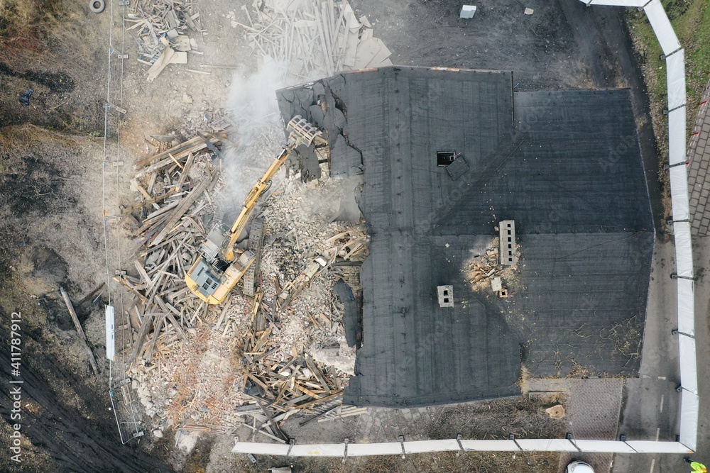 Yellow excavator destroys building. Heavy duty machine is demolishing a ...