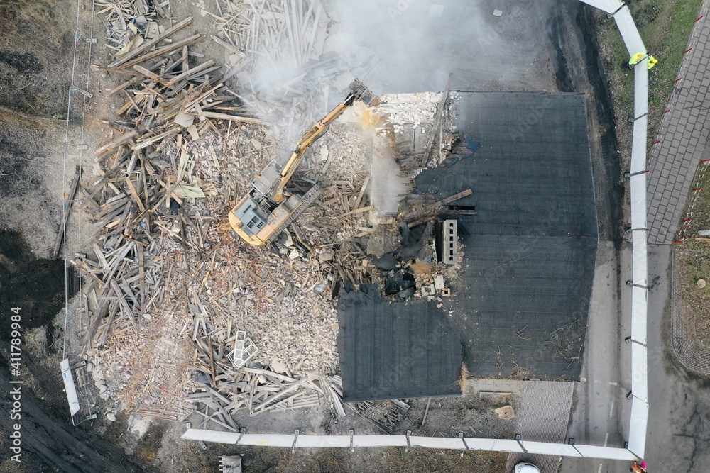 Yellow excavator destroys building. Heavy duty machine is demolishing a ...