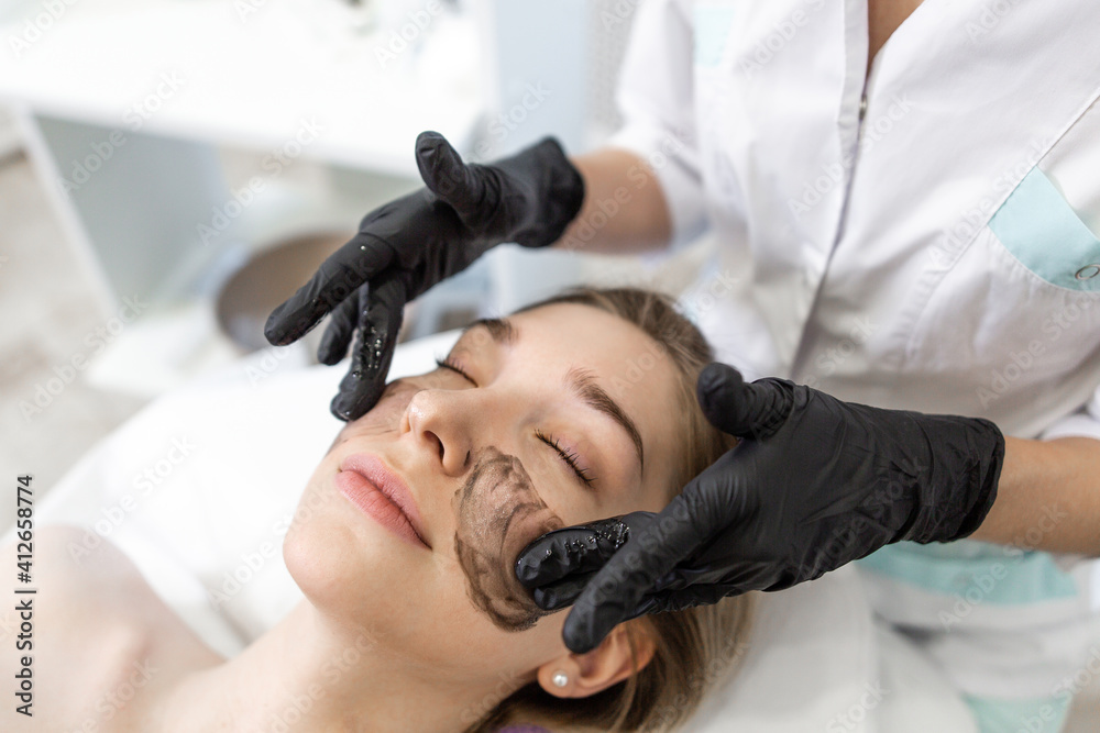 Apply a black mask to the face with massage movements. Spa treatments ...